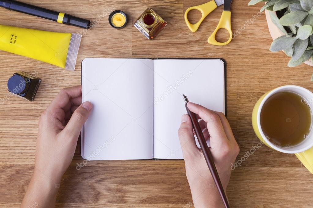 Hand with pen writing on blank notepad and yellow objects — Stock Photo ...
