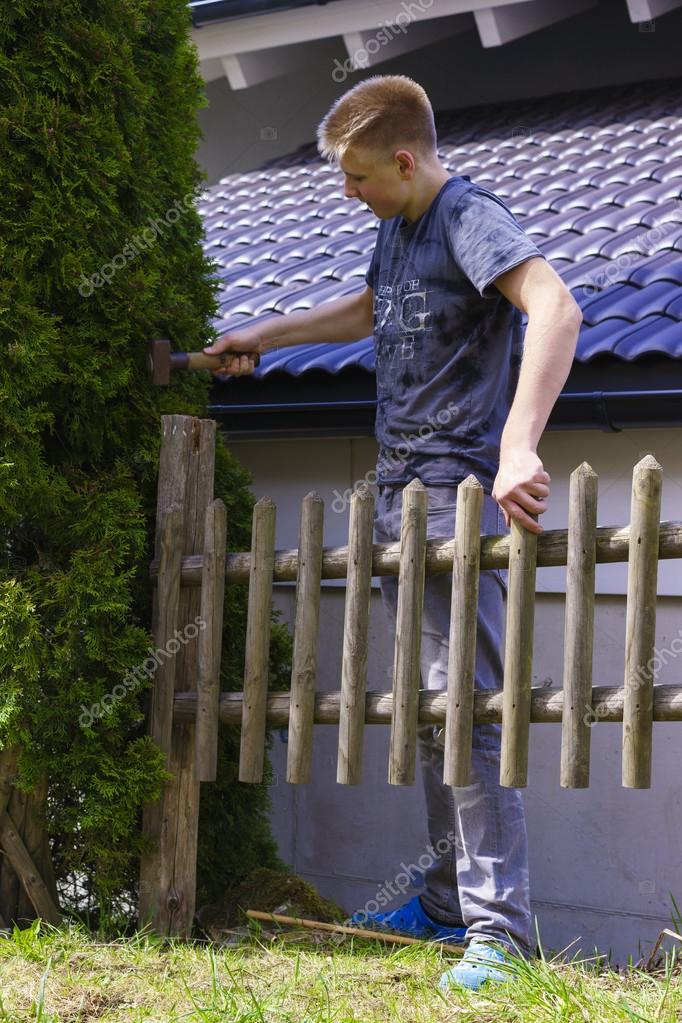 Young man working on a wooden fence — Stock Photo © elfgradost #90111870