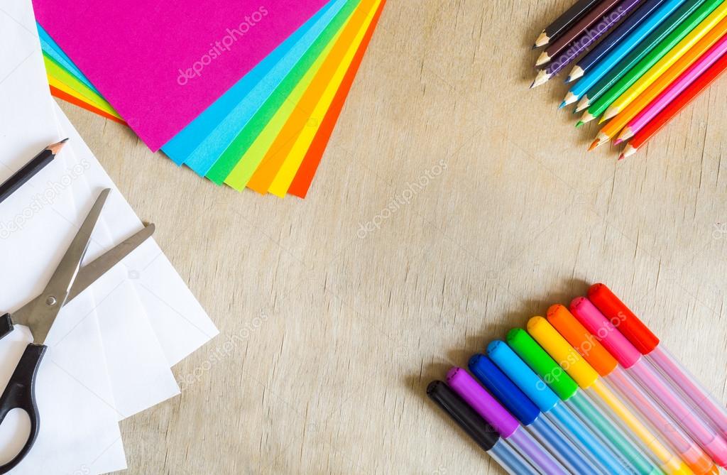 Colored paper, felt-tip pens, pencils and scissors on wooden background ...