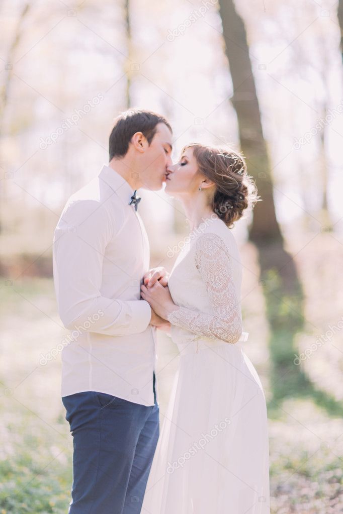 Feliz novia y novio bes ndose en el parque de primavera tomados de la mano, de cerca 2024