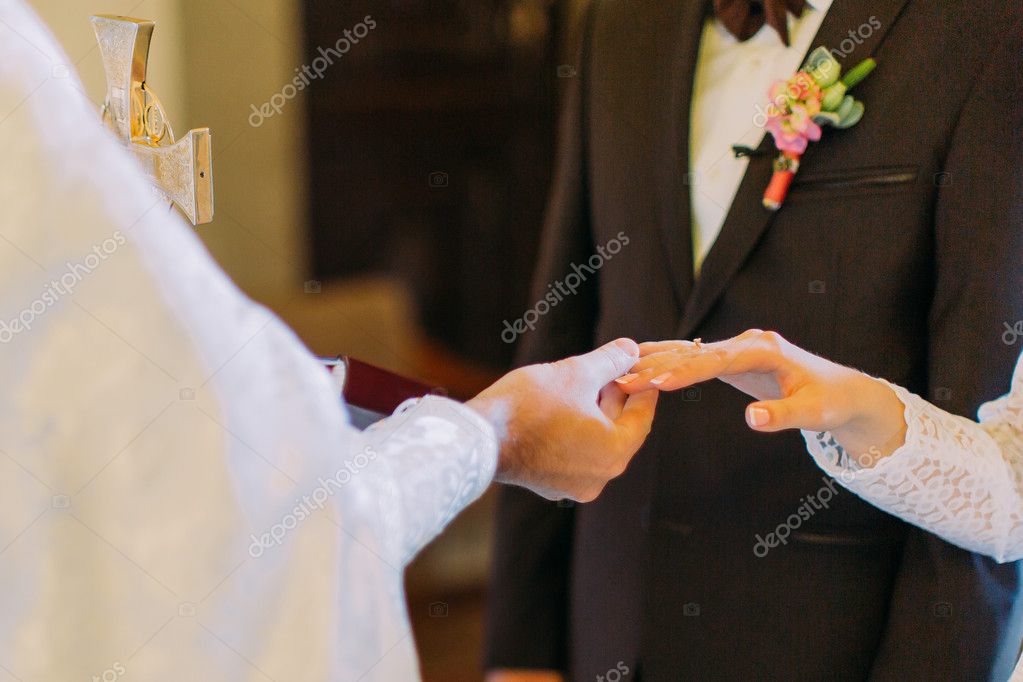 Priest is putting the ring on brides finger during wedding ceremony ...
