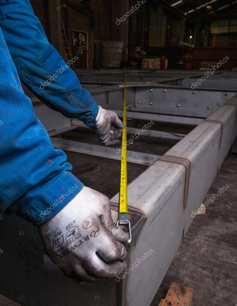 Measuring distance with a tape measure in an industrial factory setting ...