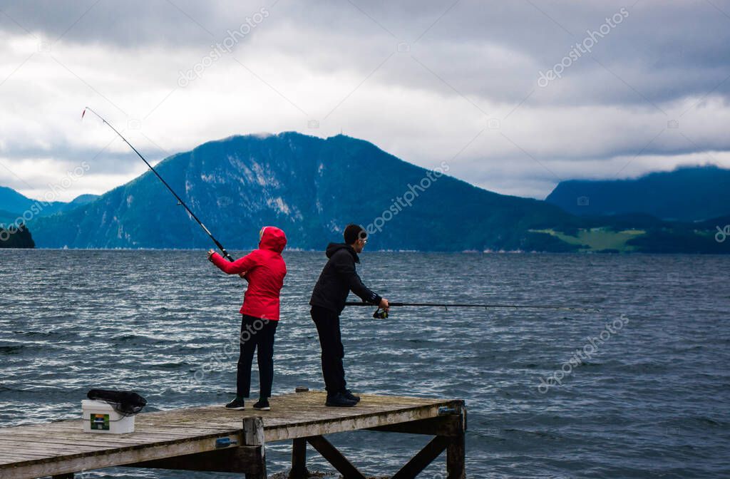 Guy y chica est n pescando con ca as de pescar. Paisaje azul dram tico ...