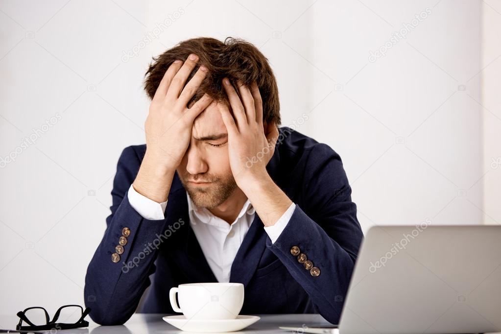 Young confused businessman sitting at the office desk — Stock Photo ... Young confused businessman sitting at the office desk — Stock Photo ...