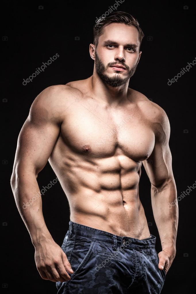 Attractive bodybuilder sportsman shows perfect body muscles on black ...