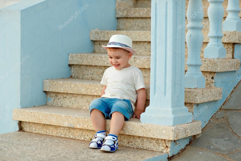 Little baby boy in the hat sitting on the steps of the house in — Stock ...