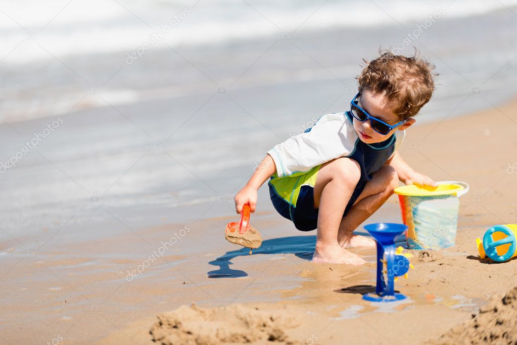 Boy playing on the beach Stock Photo by ©microgen 115108022