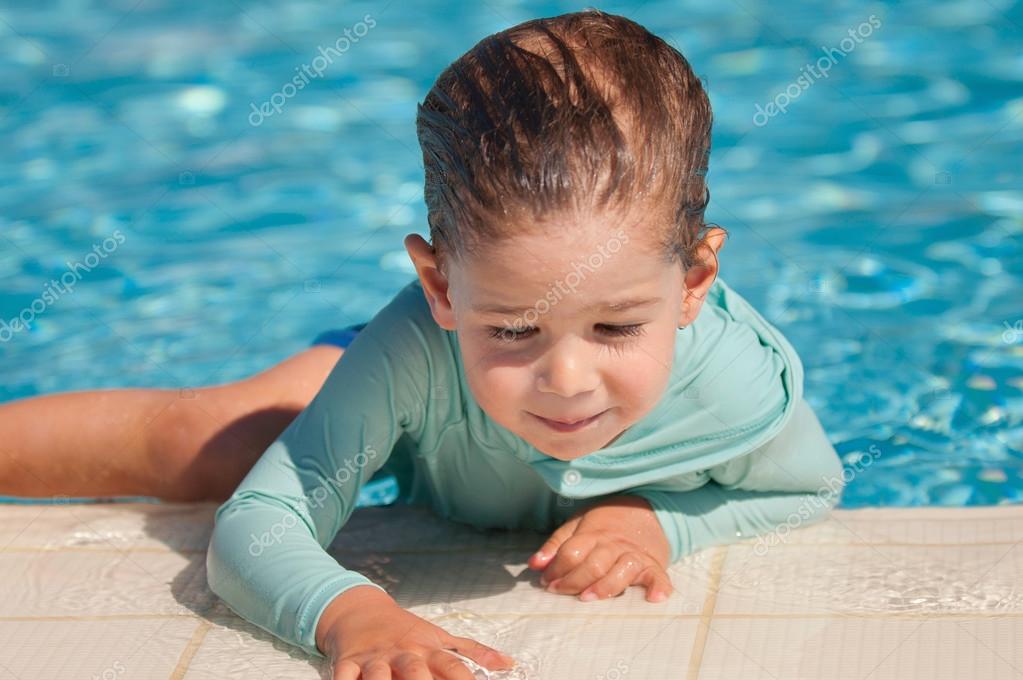 Boy climbing out of swimming pool Stock Photo by ©microgen 115181374