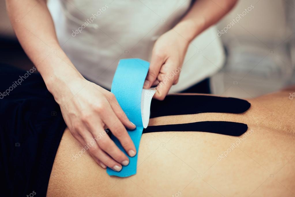 Therapist using kinesio tape on back — Stock Photo © microgen #115618792