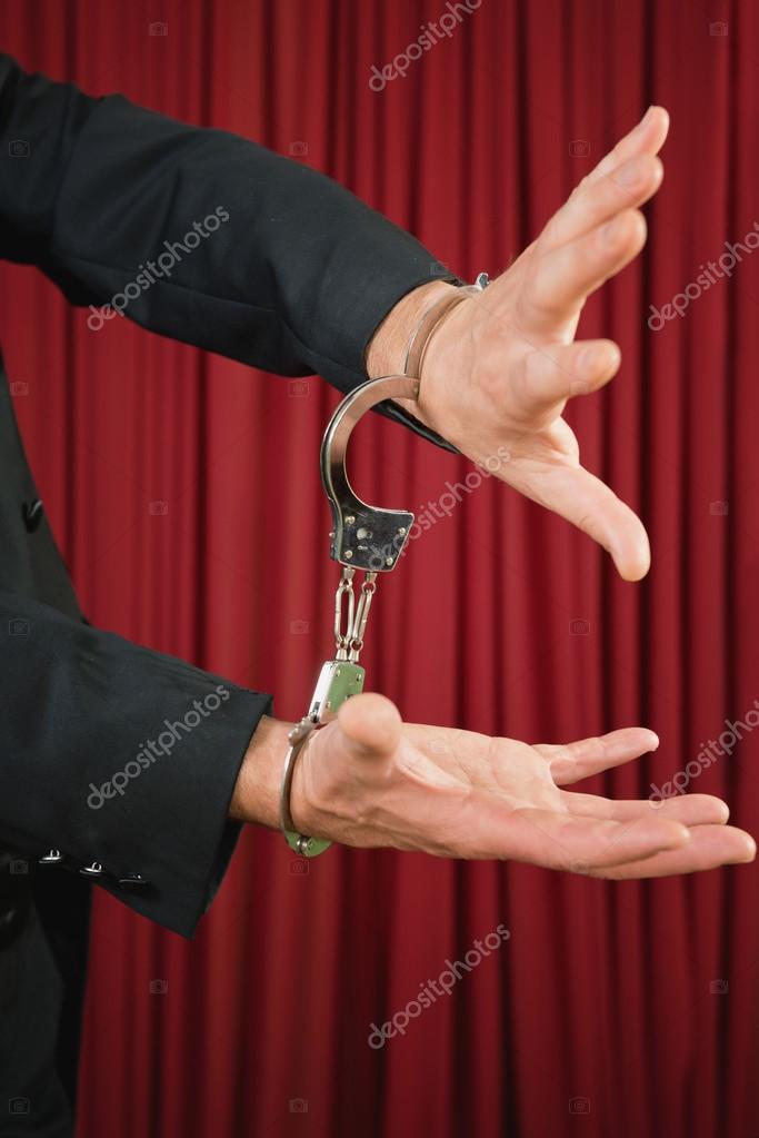 Magician unlocking handcuffs on stage Stock Photo by ©microgen 115620766