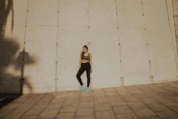 Female runner standing outdoors, taking a break after running workout ...