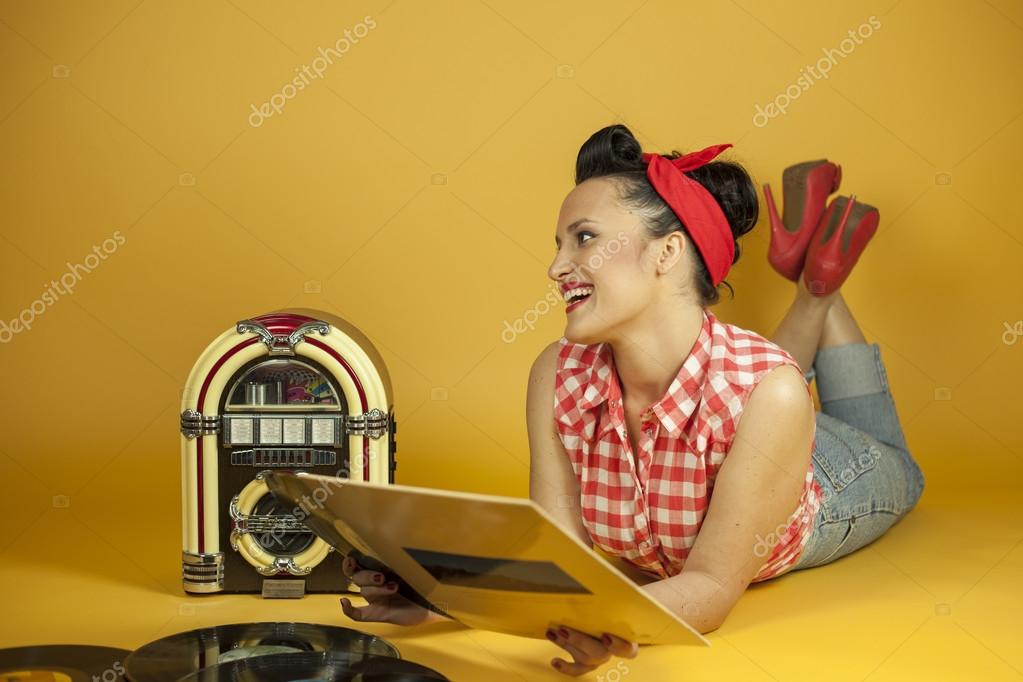 Portrait beautiful pin up listening to music on an old jukebox r ...