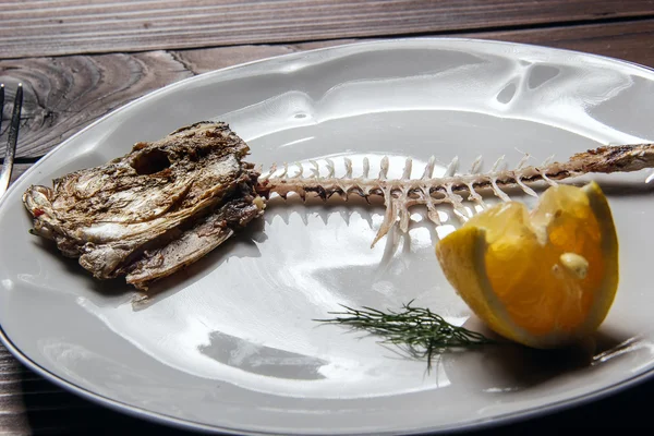 espina de pescado en el plato y limón exprimido 2024