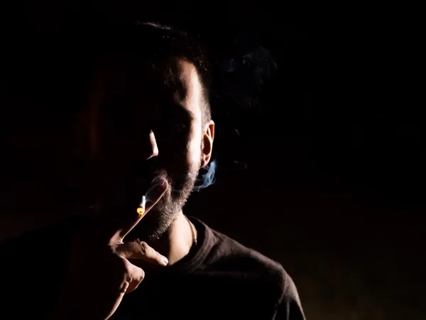Silhouette of man who lights the cigarette in the dark Stock Photo by ...