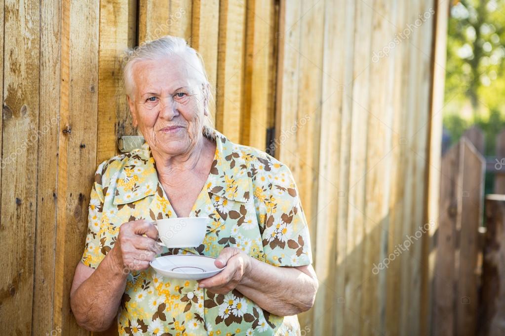 Old woman drinking tea Stock Photo by ©Scharfsinn 119682900