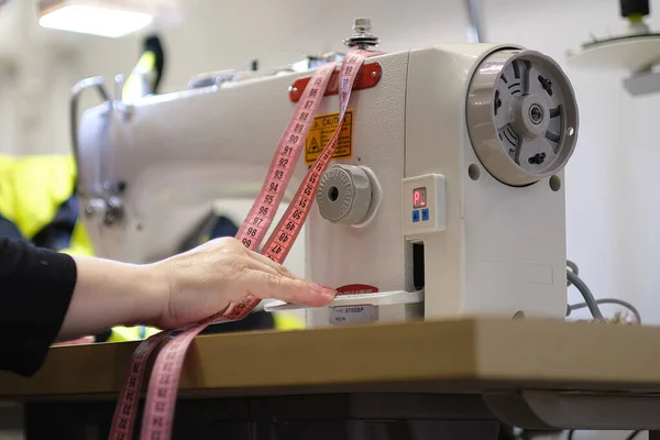 Female hands stitching white fabric on professional manufacturing ...