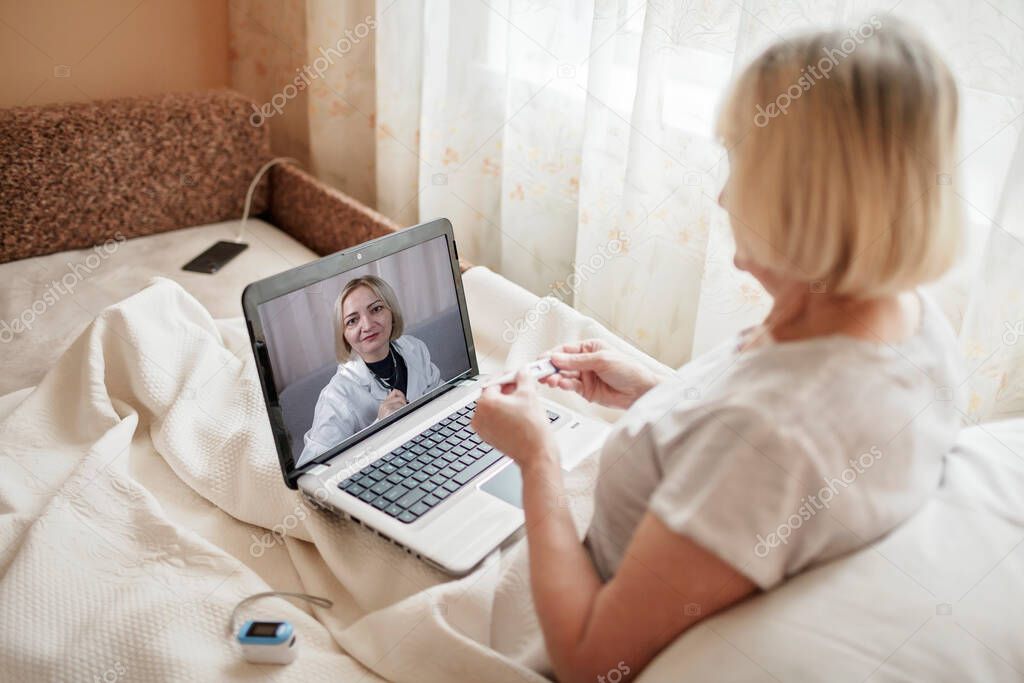 Mujer de edad en la cama mirando la pantalla de la computadora port til y consultar con un m ...