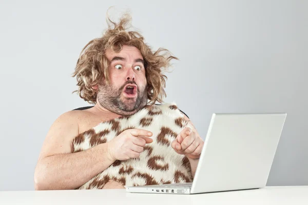 Funny perplex prehistoric man using laptop Stock Photo by ©info ...