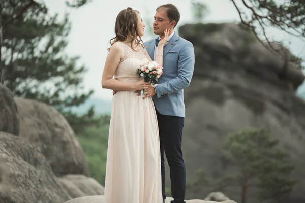 Wedding couple in love kissing and hugging near rocks on beautiful ...