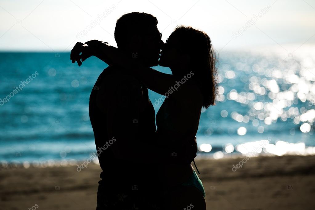 Silueta de una pareja enamorada en la playa al atardecer.Historia de amor.Hombre y una mujer en ...