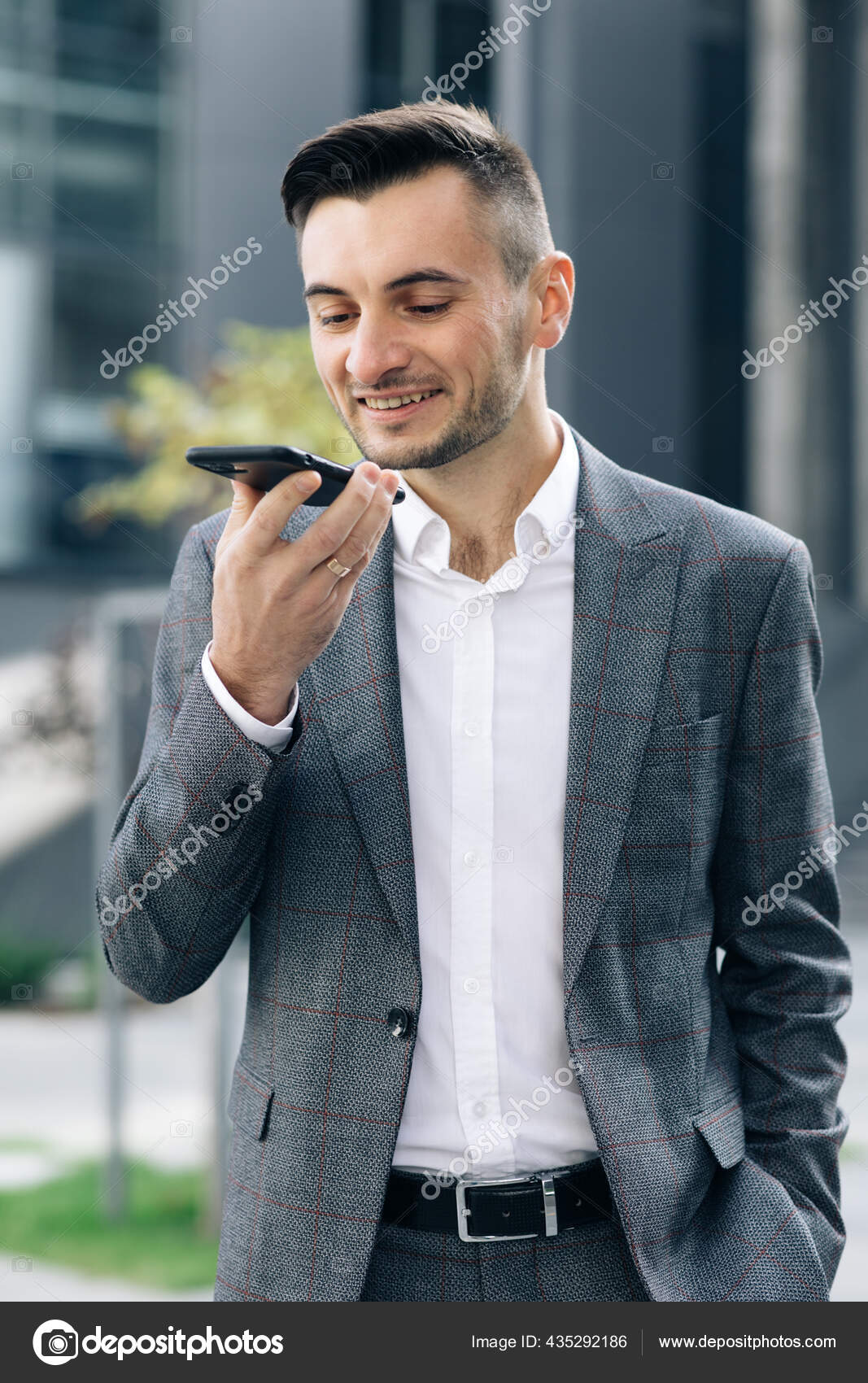 Businessman use smartphone to send voice messages outdoors at downtown ...