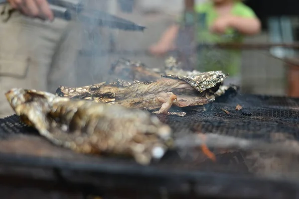 Baked fish in foil on a grill over a fire, picnic cooking. Fire and ...