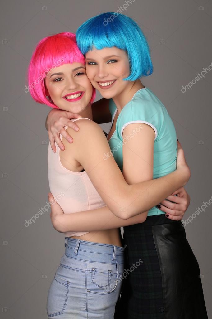 Smiling models in colorful wigs holding hands and posing. Close up ...