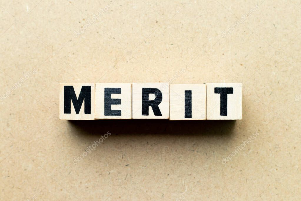 Alfabeto letra bloque en palabra mérito sobre fondo de madera 2023