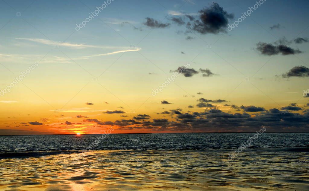 Vista de la puesta de sol que brilla en el mar y se refleja en la playa ...