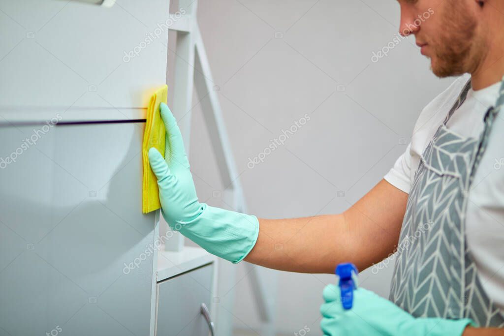 Hombre barbudo limpiando la superficie de la mesa de casa con toalla y ...