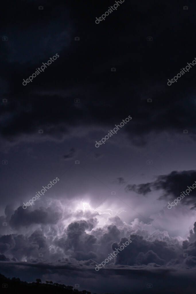 Fuerte rayo en y detrás de grandes nubes de trueno 2024