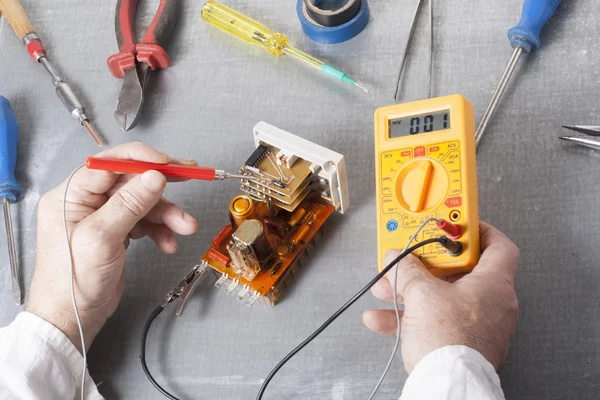 Hand of electrician with multimeter probe at electrical switchgear ...
