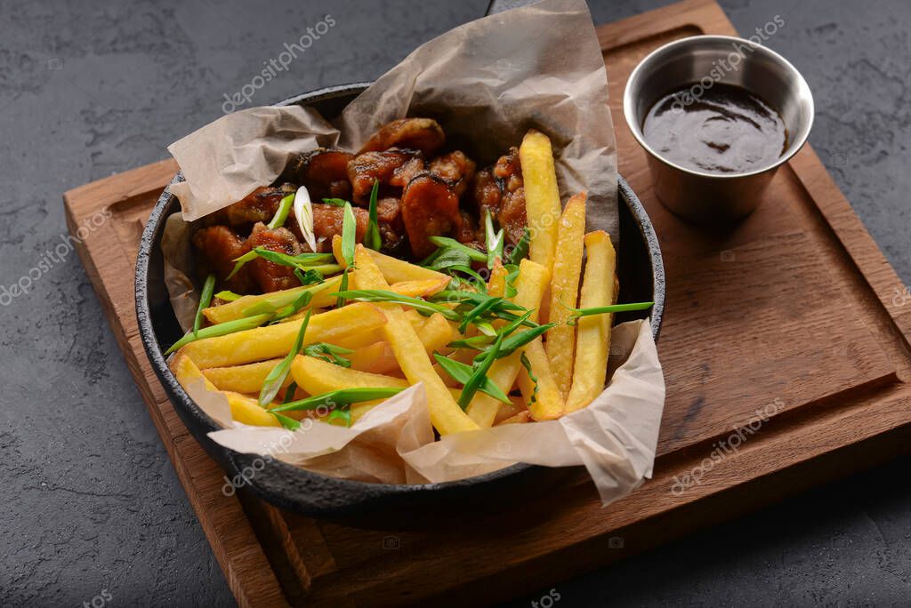 Patatas fritas en una sartén de hierro sobre tabla de madera rústica y ...