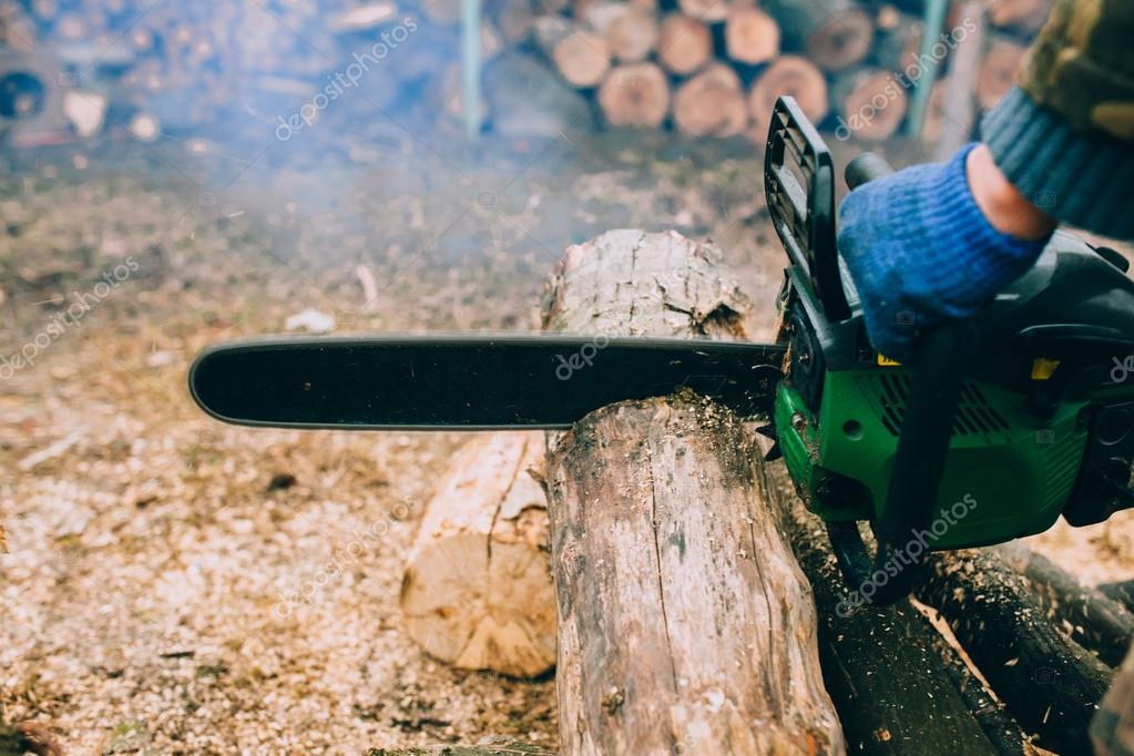 Male hands cutting trunk with chainsaw — Stock Photo © Amvorsuf #111773530