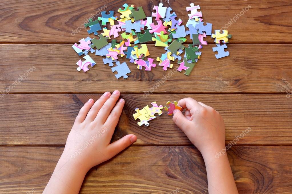 Child holding puzzles in hands. A set of colorful jigsaw puzzles pieces ...