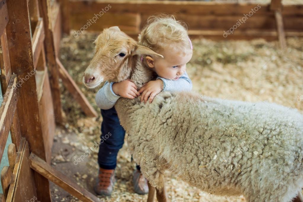 Girl hugging lamb — Stock Photo © galitskaya #118267586