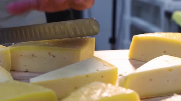 Man worker cutting off triangle pieces of cheese with a knife on the ...
