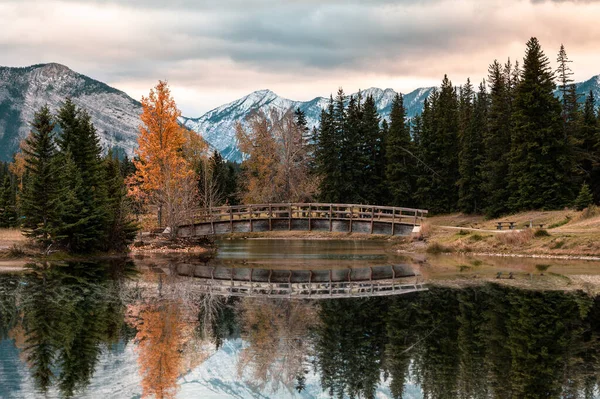Wooden bridge in autumn forest reflection on Cascade ponds at Banff ...