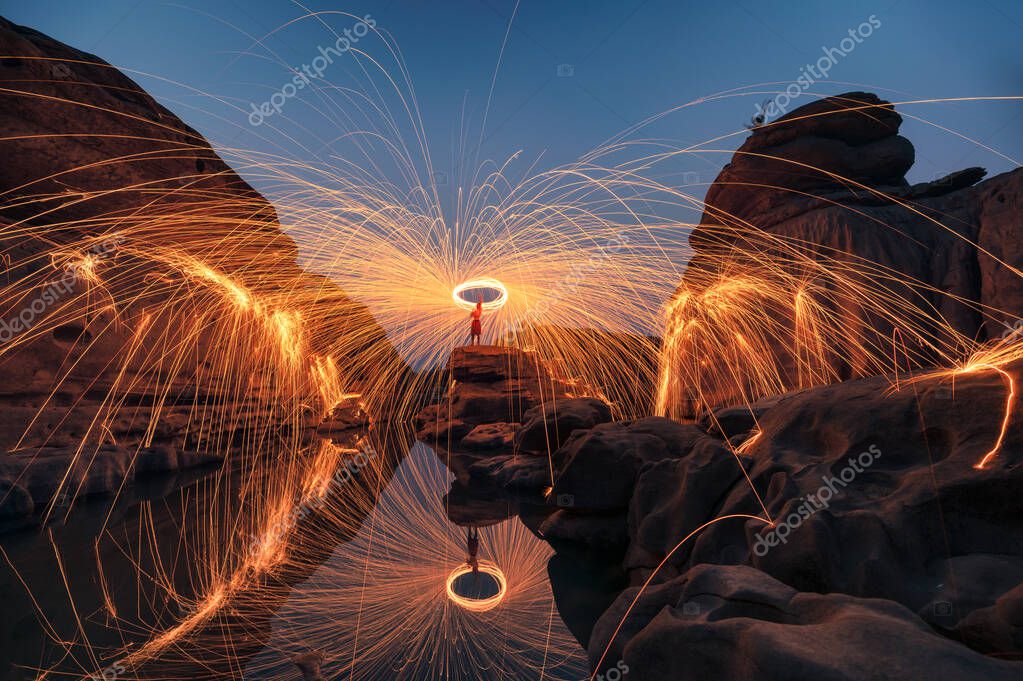 Hombre empuñando fuego ardiente redondeado chispa de lana de acero en ...