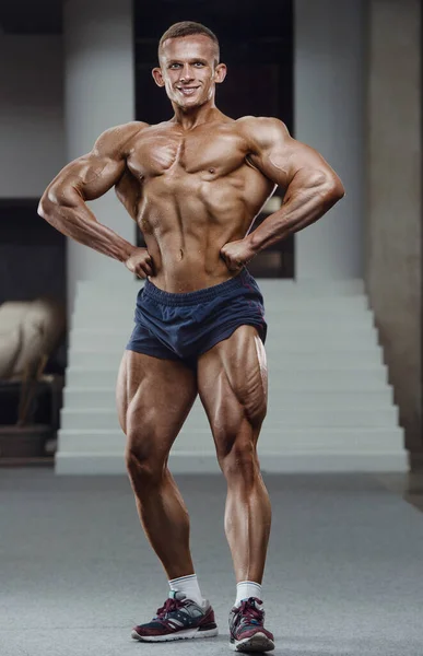 Caucasian power athletic man training pumping up leg quadriceps muscles. Strong bodybuilder with ...