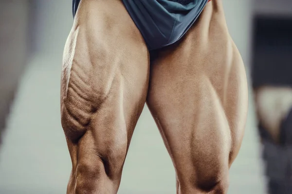 Caucasian power athletic man training pumping up leg quadriceps muscles. Strong bodybuilder with ...