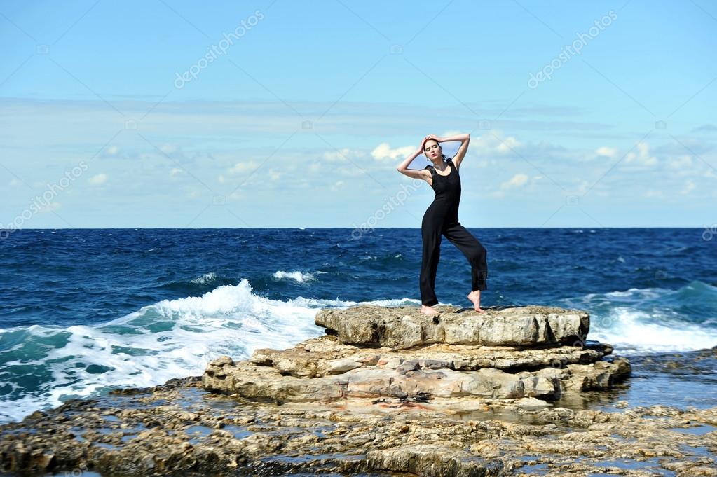 Beautiful young fashion model posing on the rocks with nice dress ...