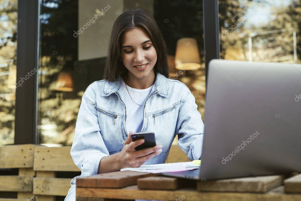 Joven mujer de negocios que trabaja en la terraza abierta en casa, sentada frente a la ...