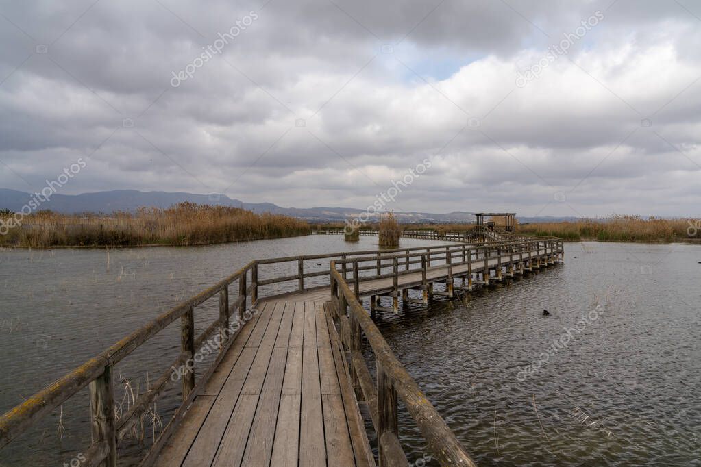 Un largo muelle de madera y paseo marítimo en humedales de agua salobre ...