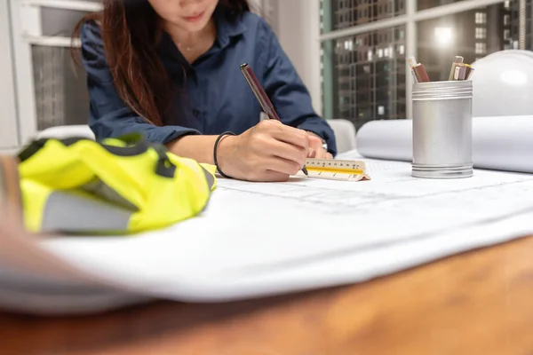 Ingeniera Diseñadora bosquejando con Blueprint Architecture en la oficina de escritorio en casa ...