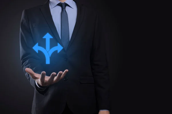Businessman in a suit holds a sign showing three directions. in doubt ...
