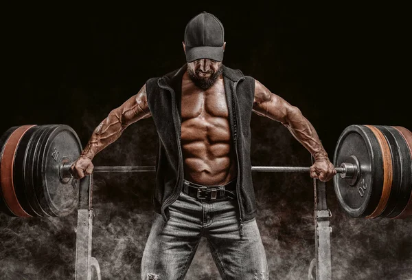 Muscular bearded man stands near the barbell. Bodybuilding, fitness ...