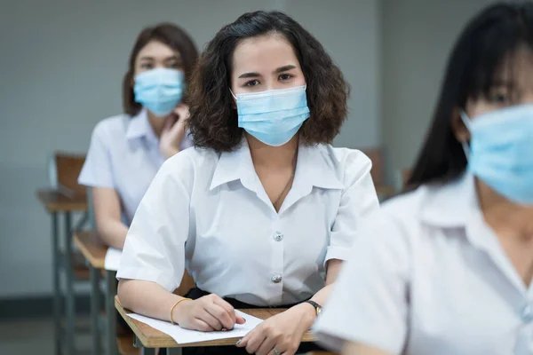Cheerful college students in the classroom wear protective face masks ...