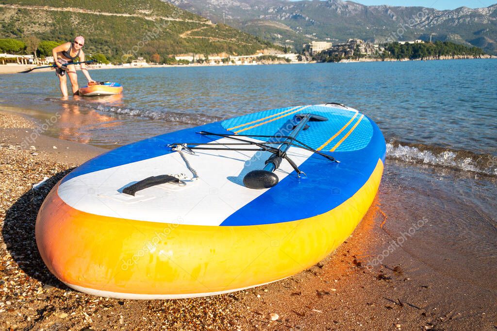 El primer plano de una tabla de remo se encuentra en la costa, se seca, después de un viaje ...
