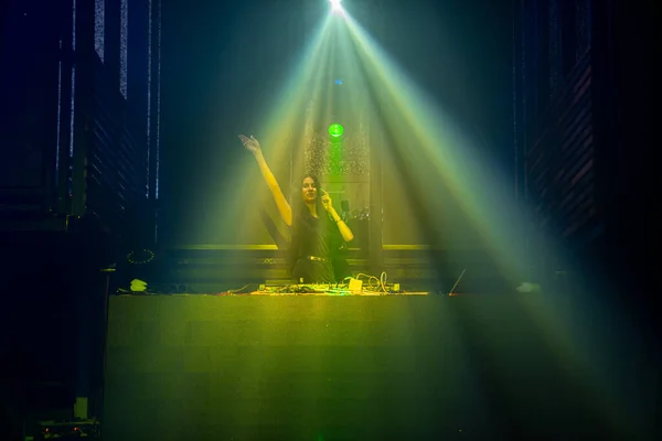 Group of people dance in disco night club to the beat of music from DJ ...